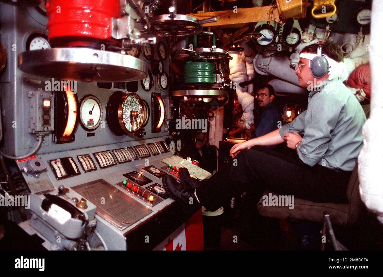 Sailors monitor the gauges on a control panel in the engine room aboard ...