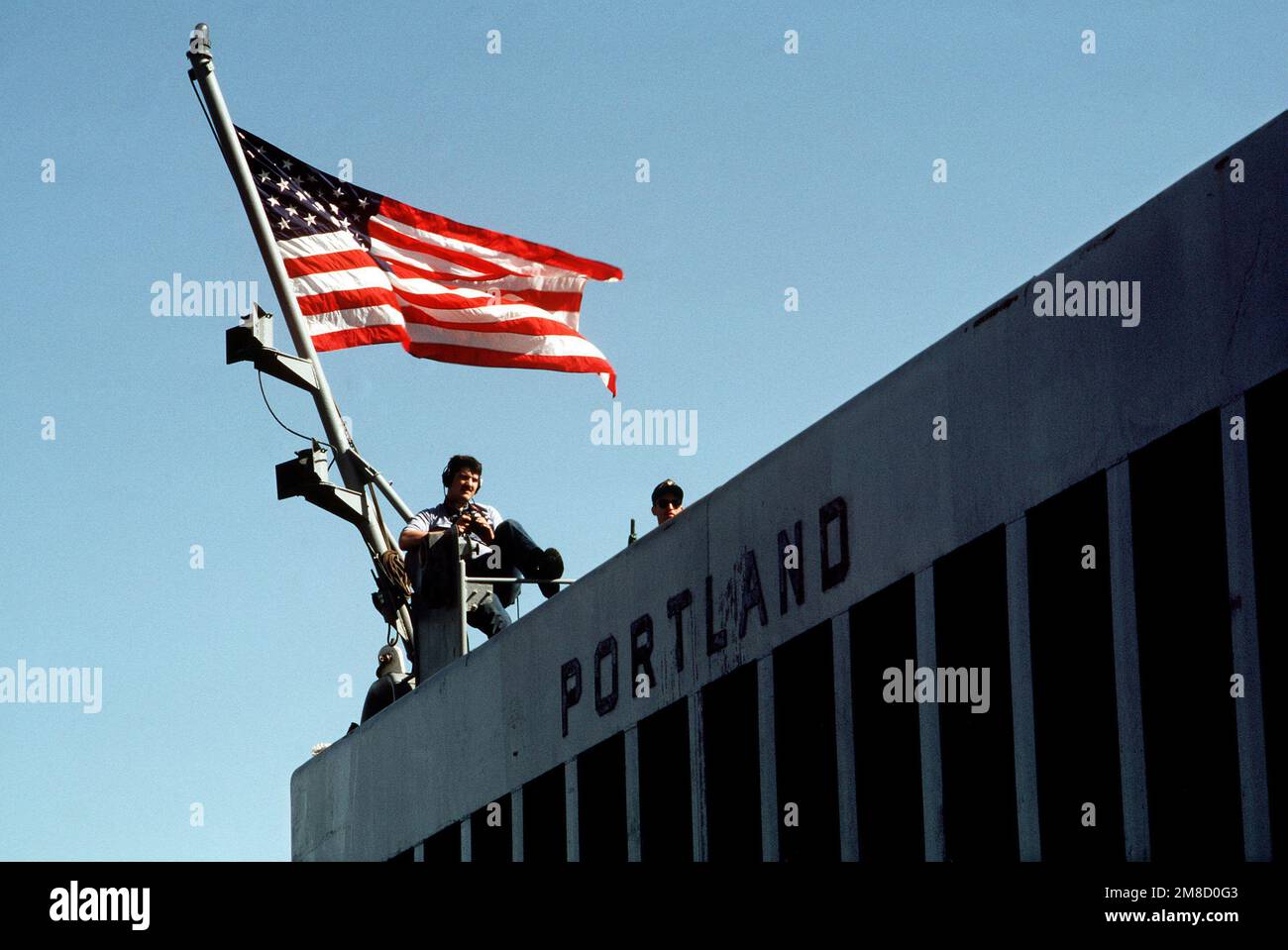 A crew member looks down from the stern of the dock landing ship USS ...