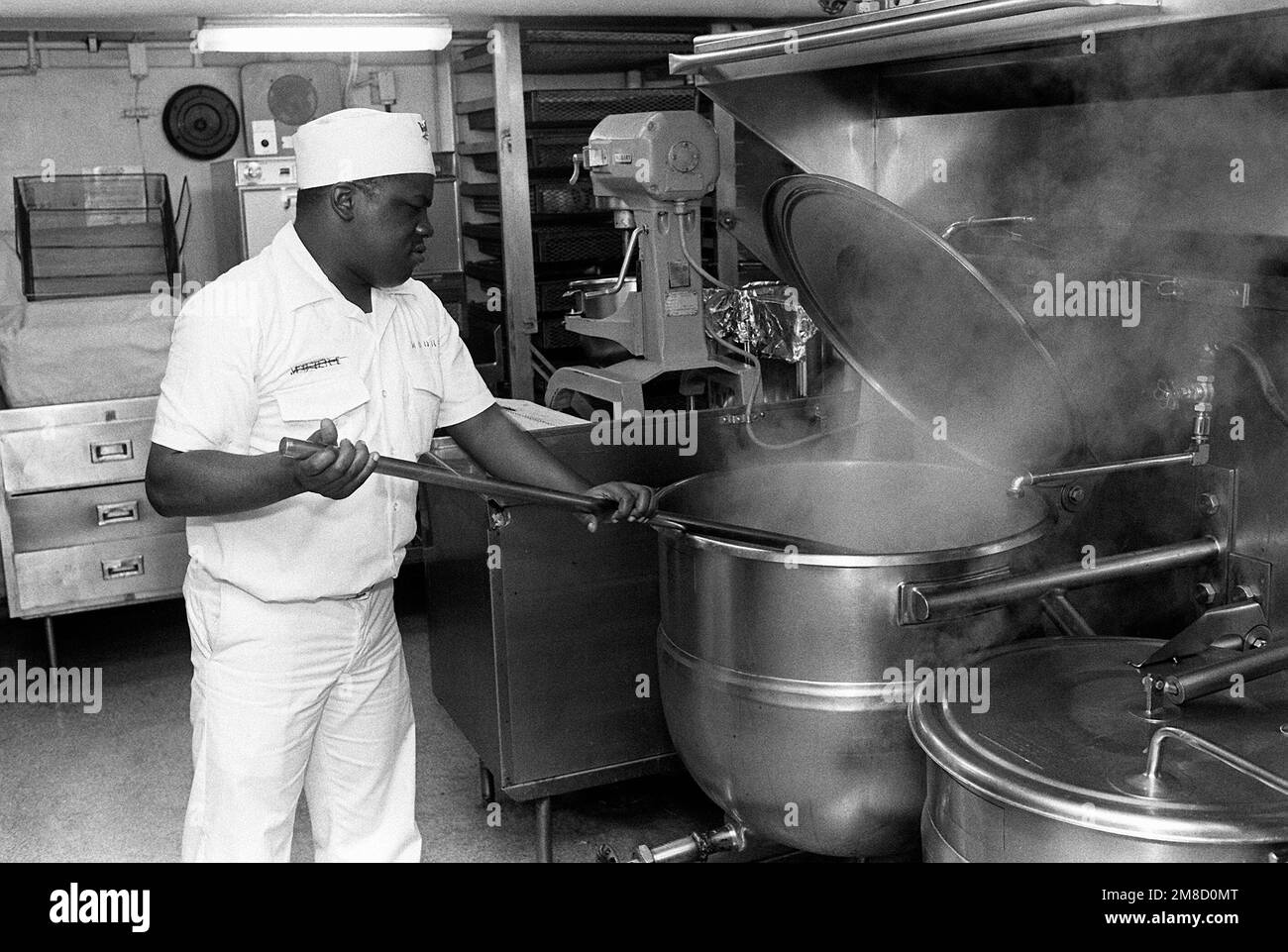 A mess management specialist prepares a meal in the galley of the ...