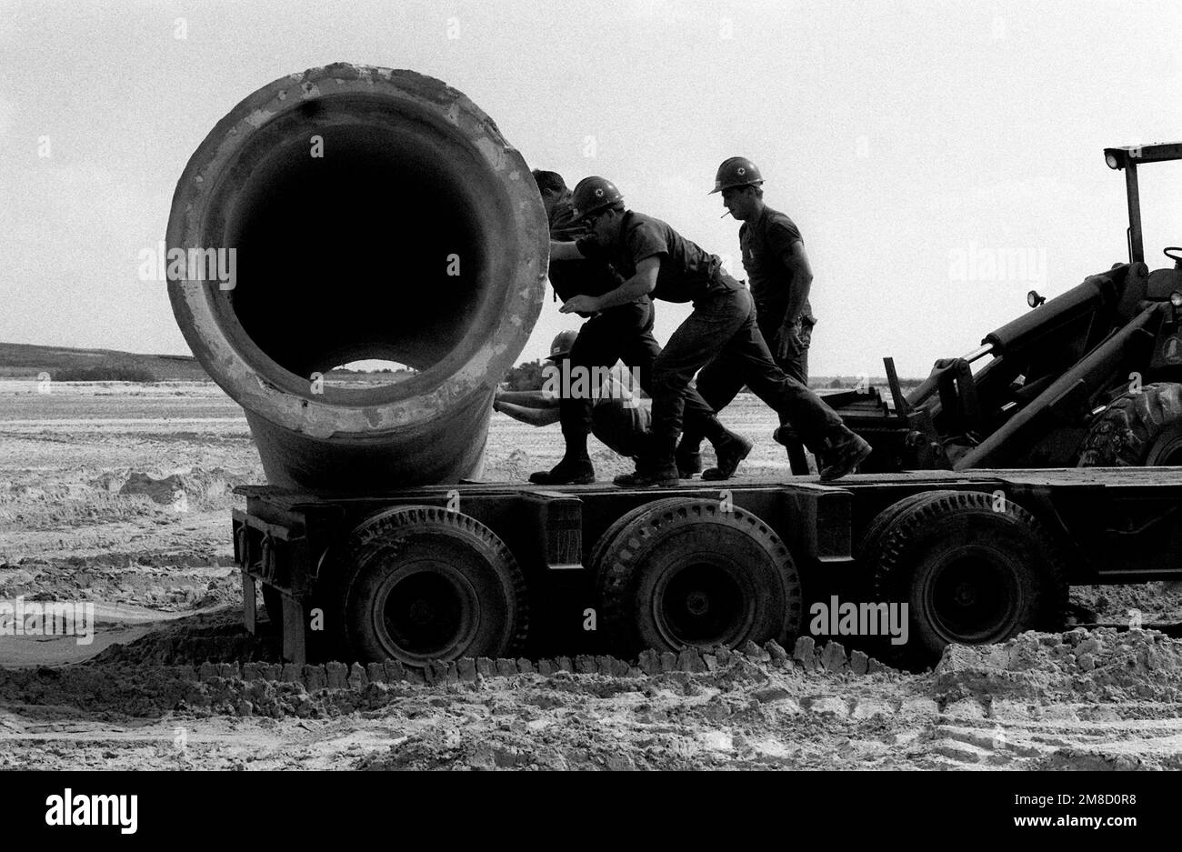 US Navy Seabees push a cement culvert from a trailer during exercise ...