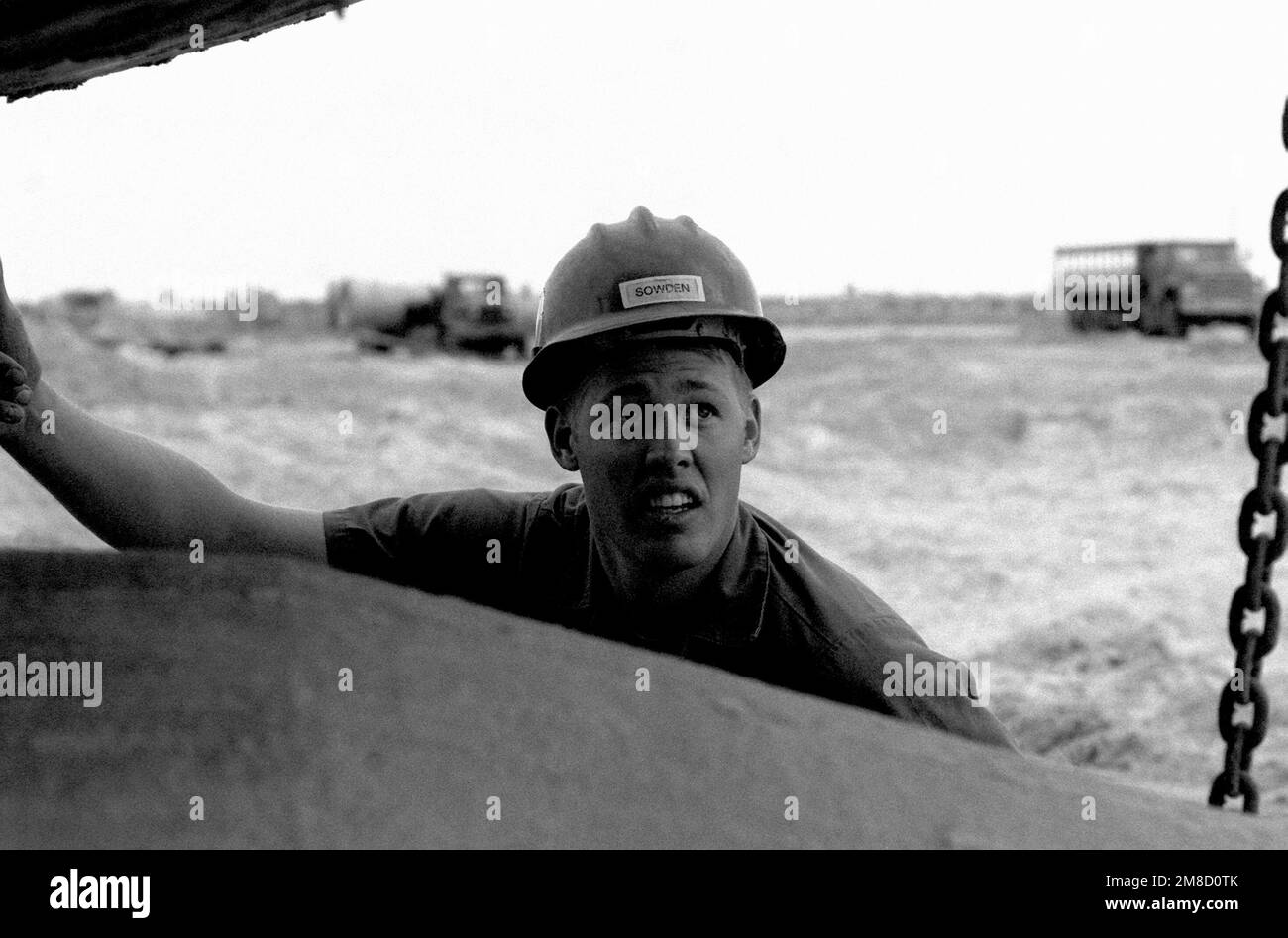 A US Navy Seabee signals to an equipment operator as the Seabees work ...