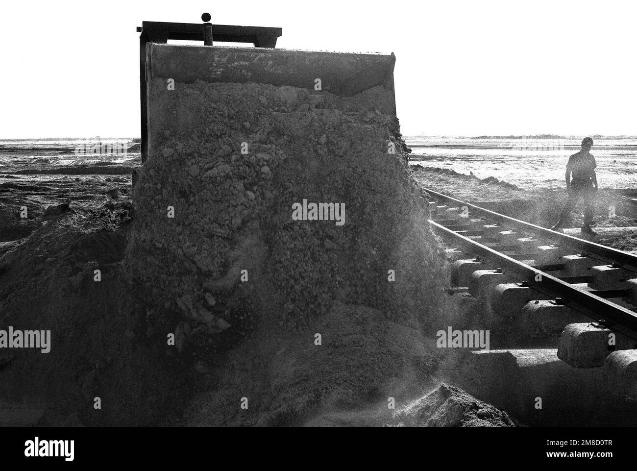 A crawler tractor deposits a load of backfill on top of cement culverts ...