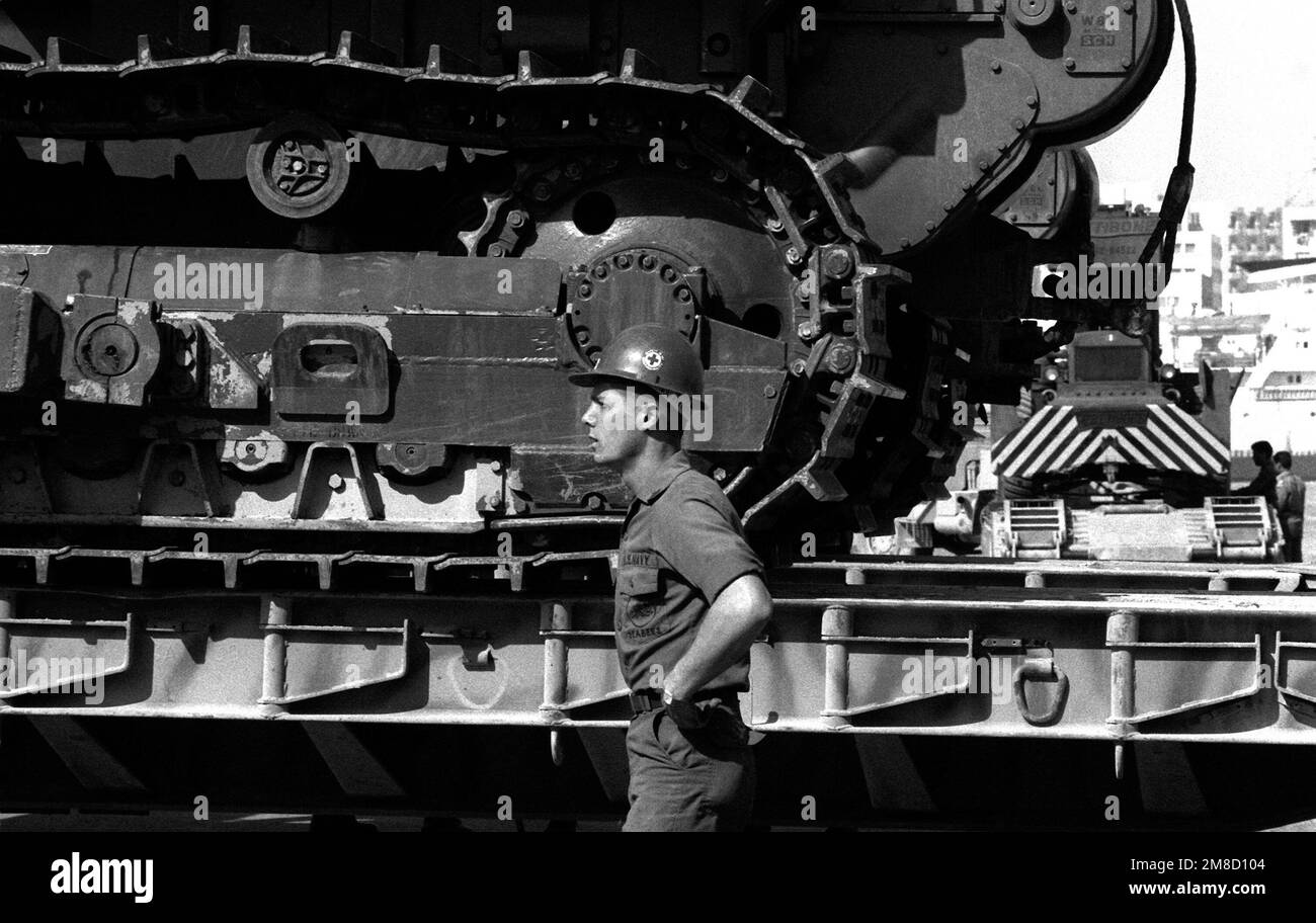 A US Navy Seabee supervises the unloading of equipment from the dock ...