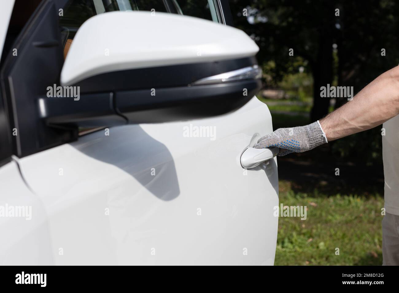 a man in gloves opens the door of a white car. hand opens car door ...