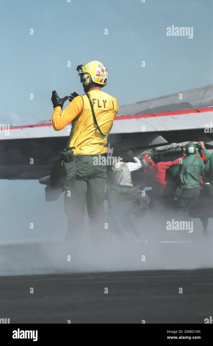 A plane director guides an aircraft into place on the No. 1 catapult ...