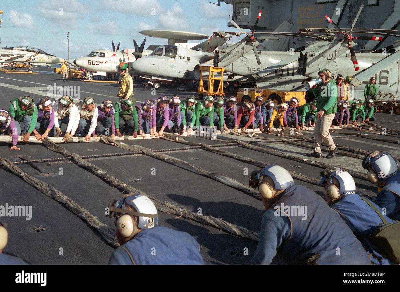 Flight deck crewmen rig the crash barricade during a drill aboard the ...