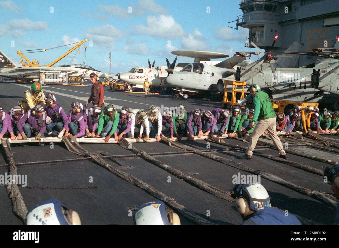Flight deck crewmen rig the crash barricade during a drill aboard the ...
