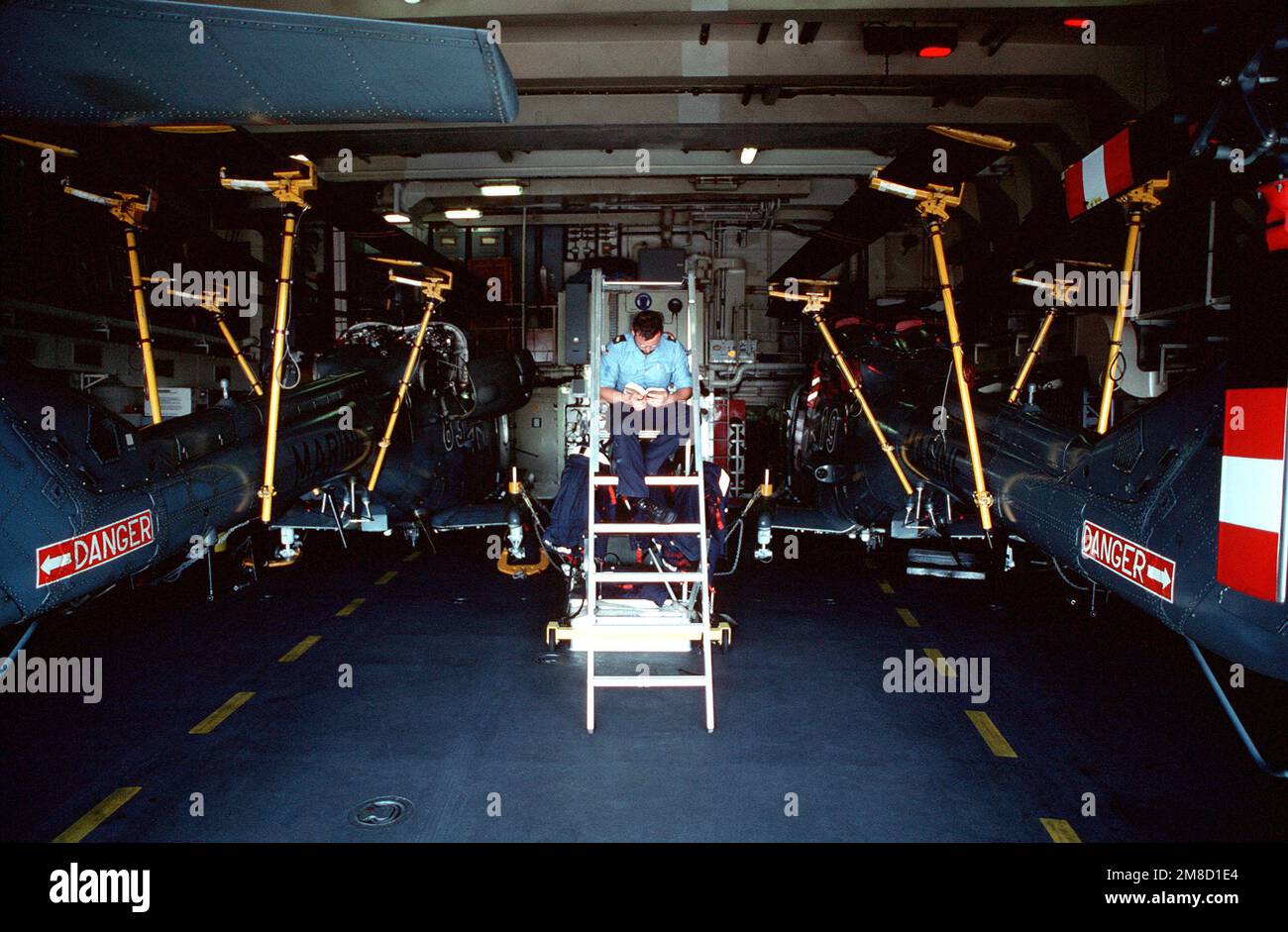 A sailor reads a book while sitting on a ladder between two Mark 88 ...
