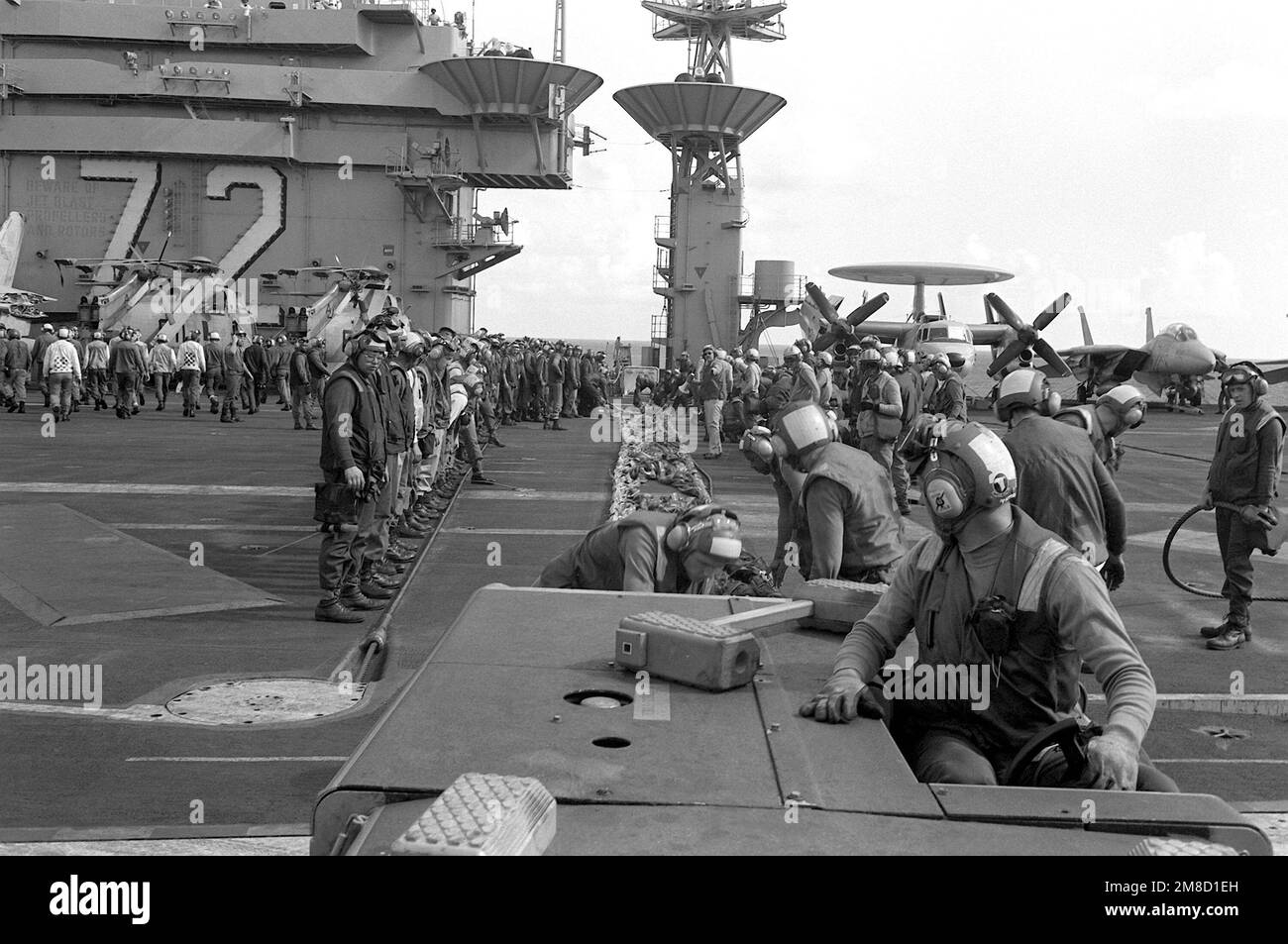 Flight deck crewmen stand by as the crash barricade is pulled from its ...
