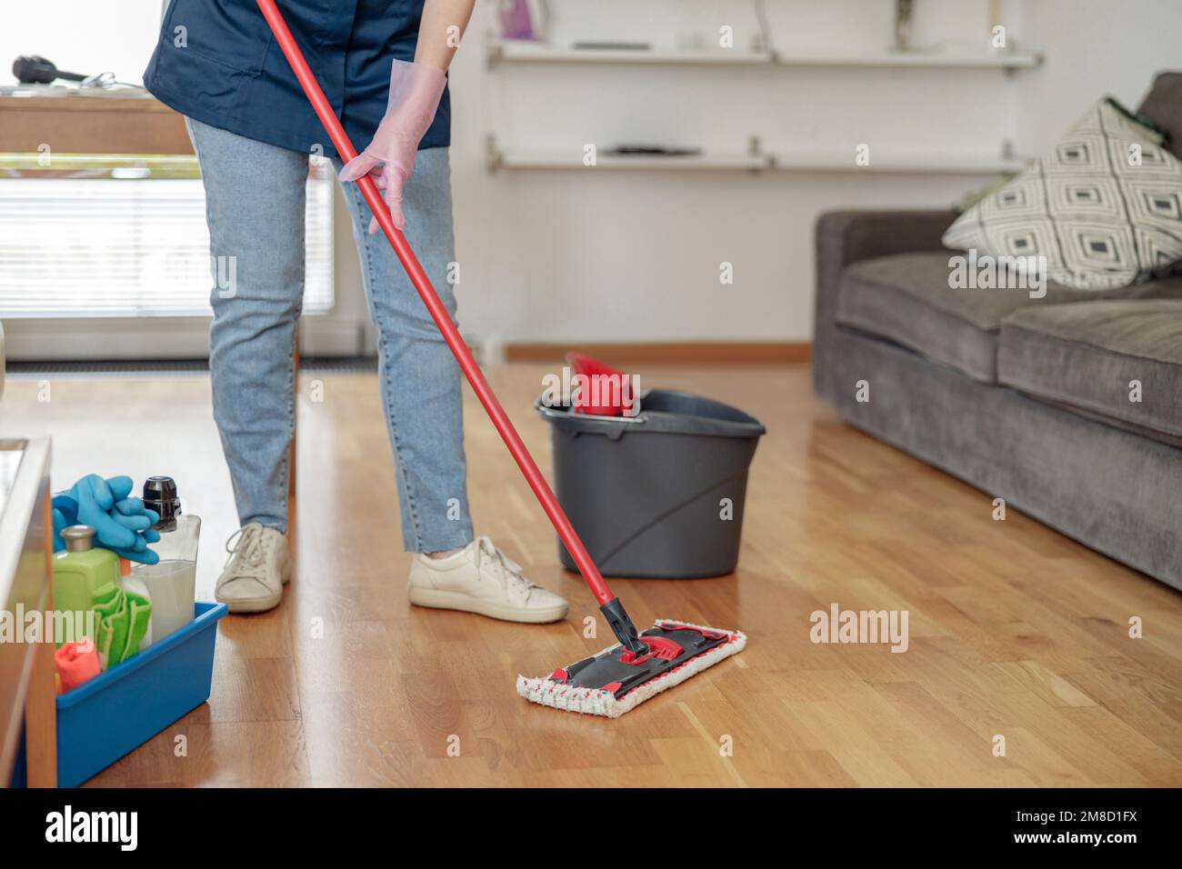 Unrecognizable woman washing floor with mop in living room ...
