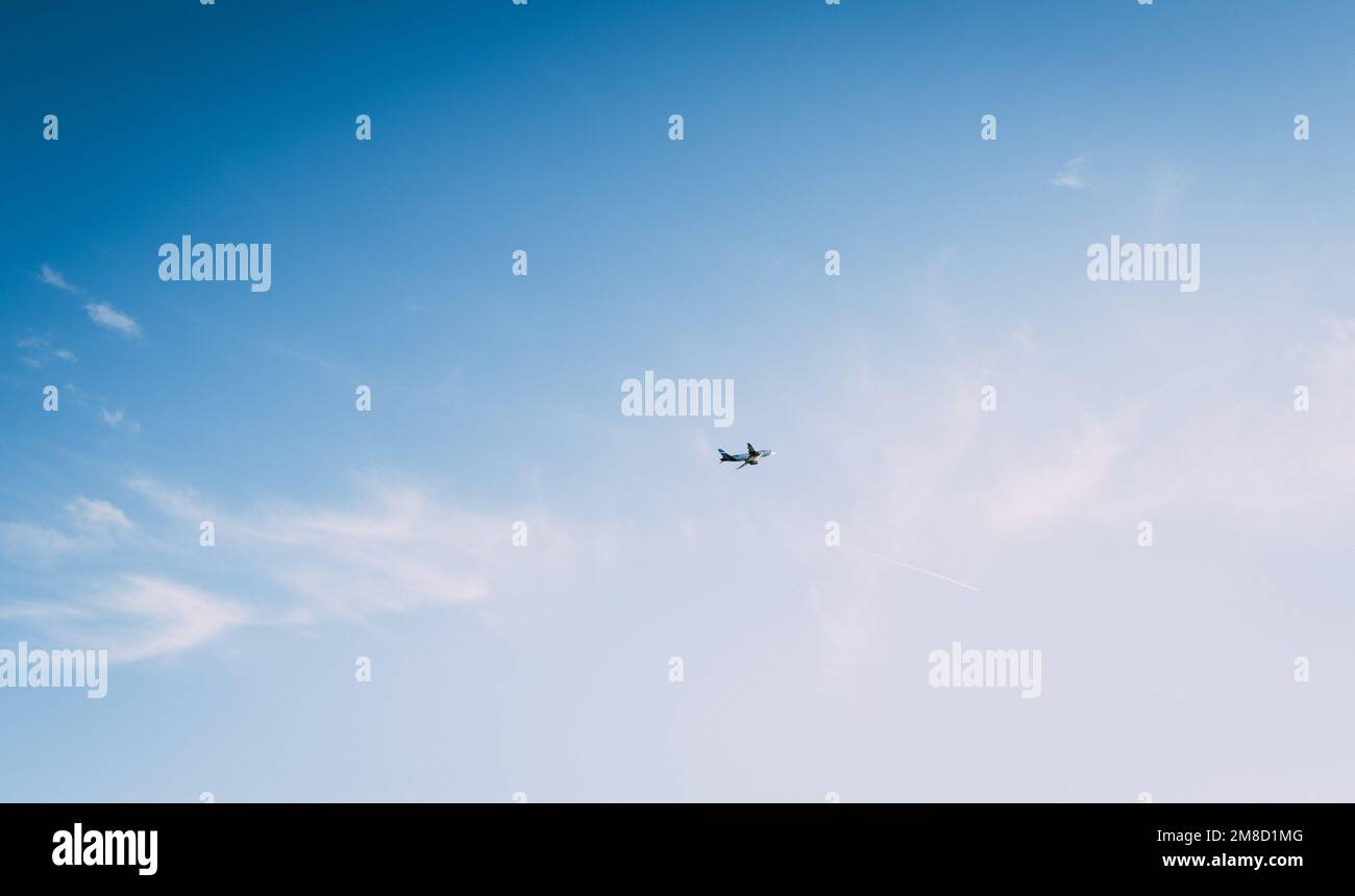 A low angle shot of a plane flying in a blue sky Stock Photo - Alamy