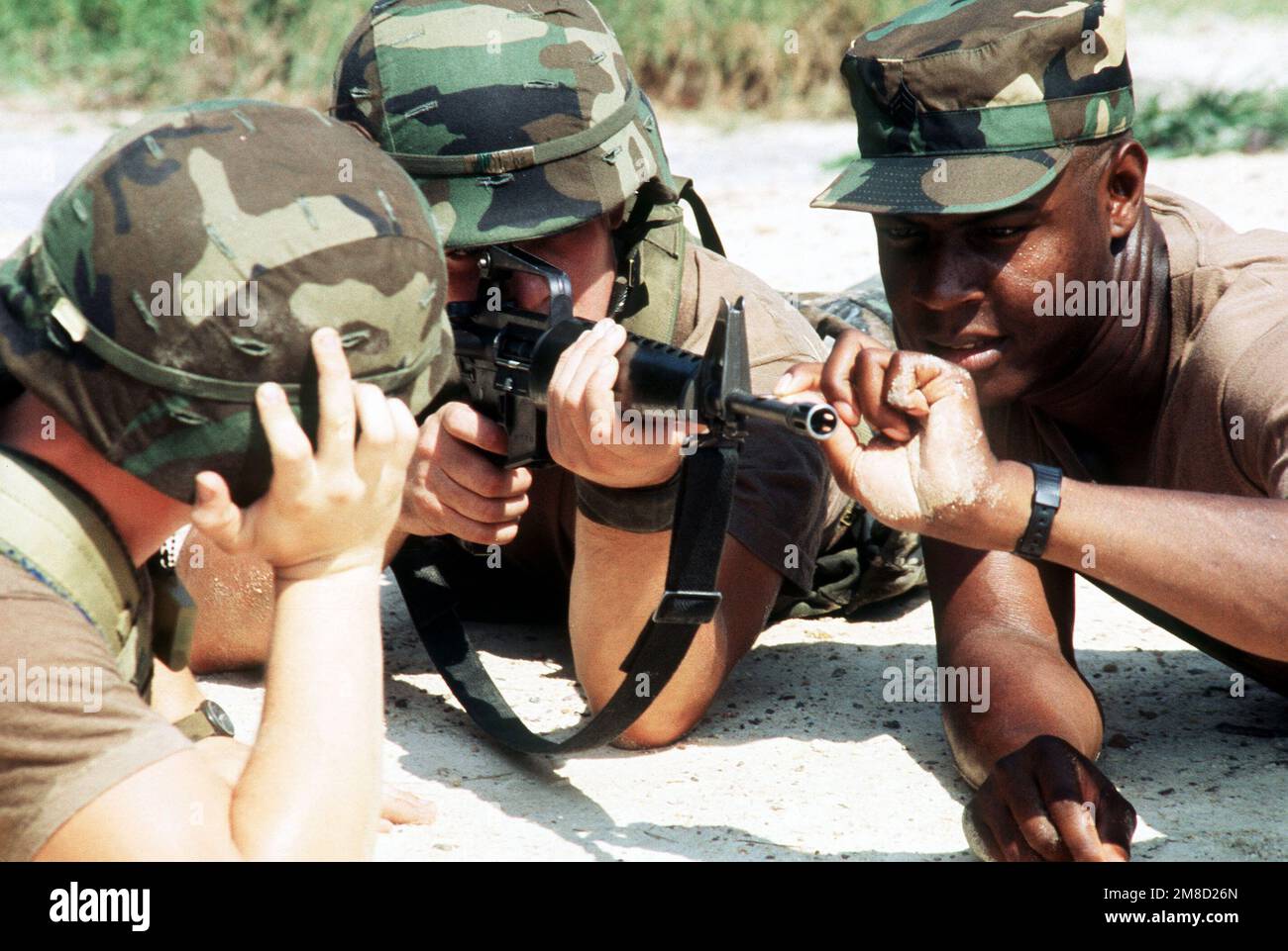 An instructor helps a recruit align an M-16A1 during basic training ...