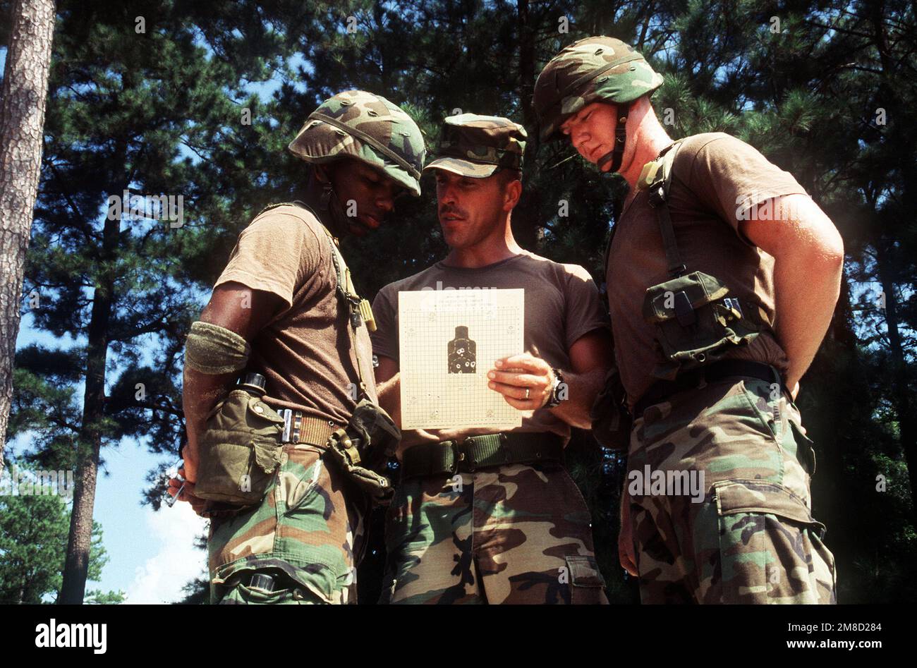 An instructor and two recruits review a rifle qualification score ...