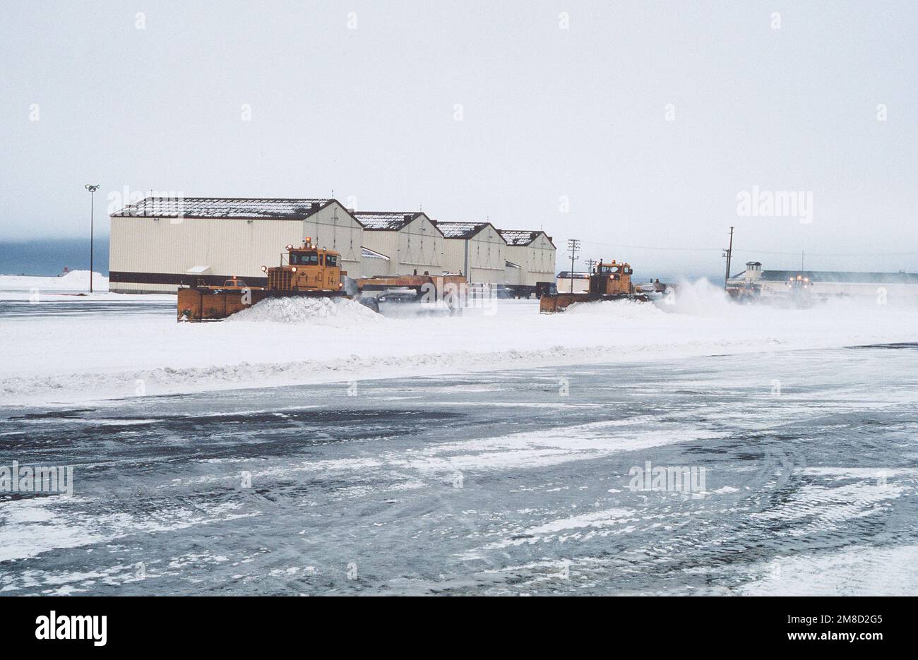 Heavy equipment removes snow in front of hangars on the flight line ...