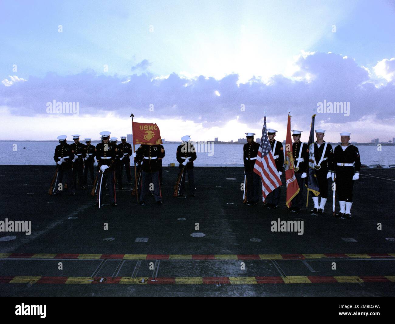 A joint Marine Corps/Navy color guard stands at attention beside ...