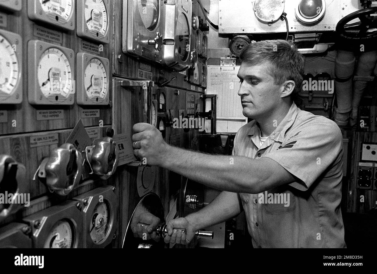 A petty officer works at a control panel for the No. 3 main generator ...