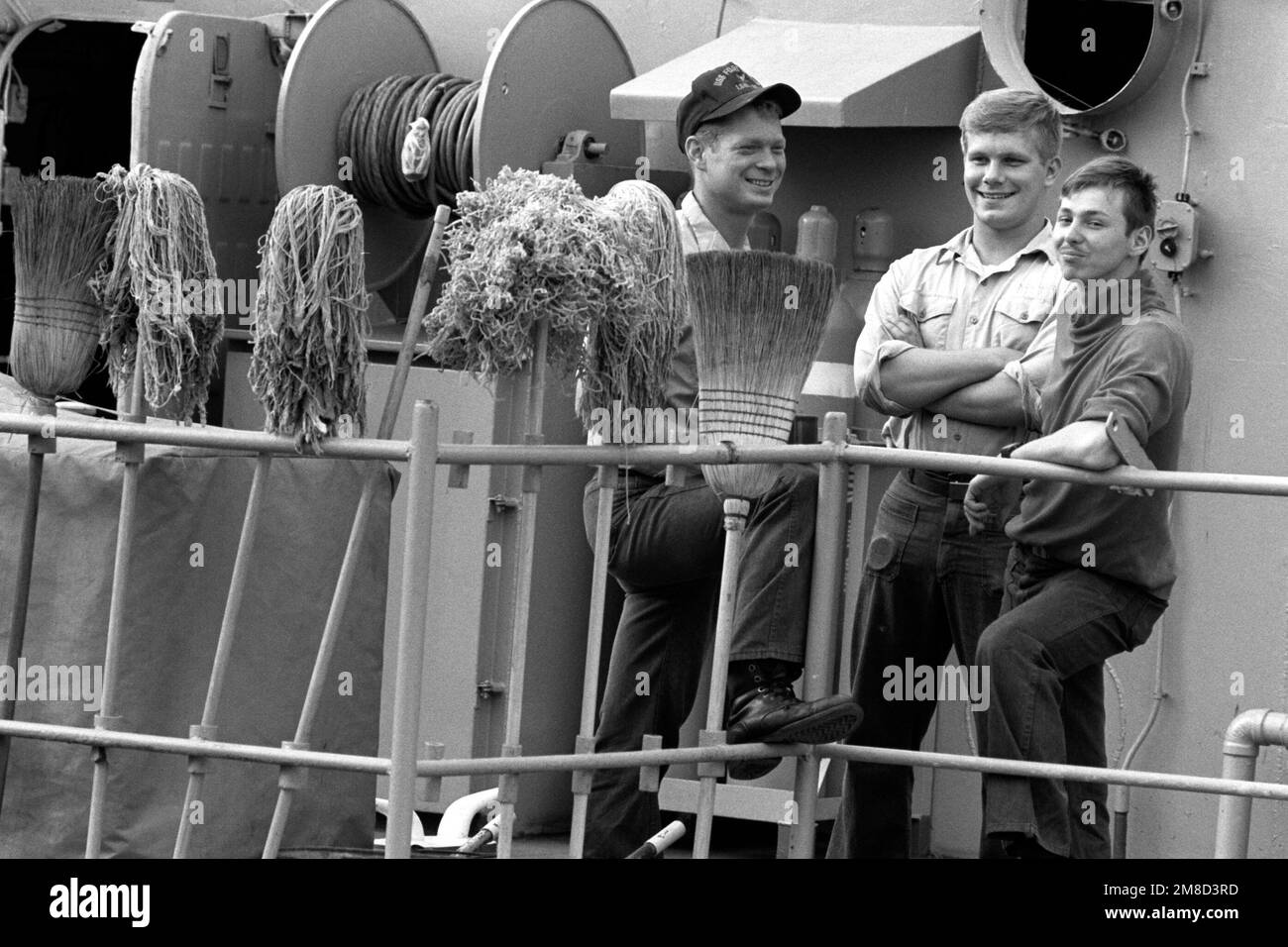 Three sailors relax near a swab rack aboard the dock landing ship USS ...