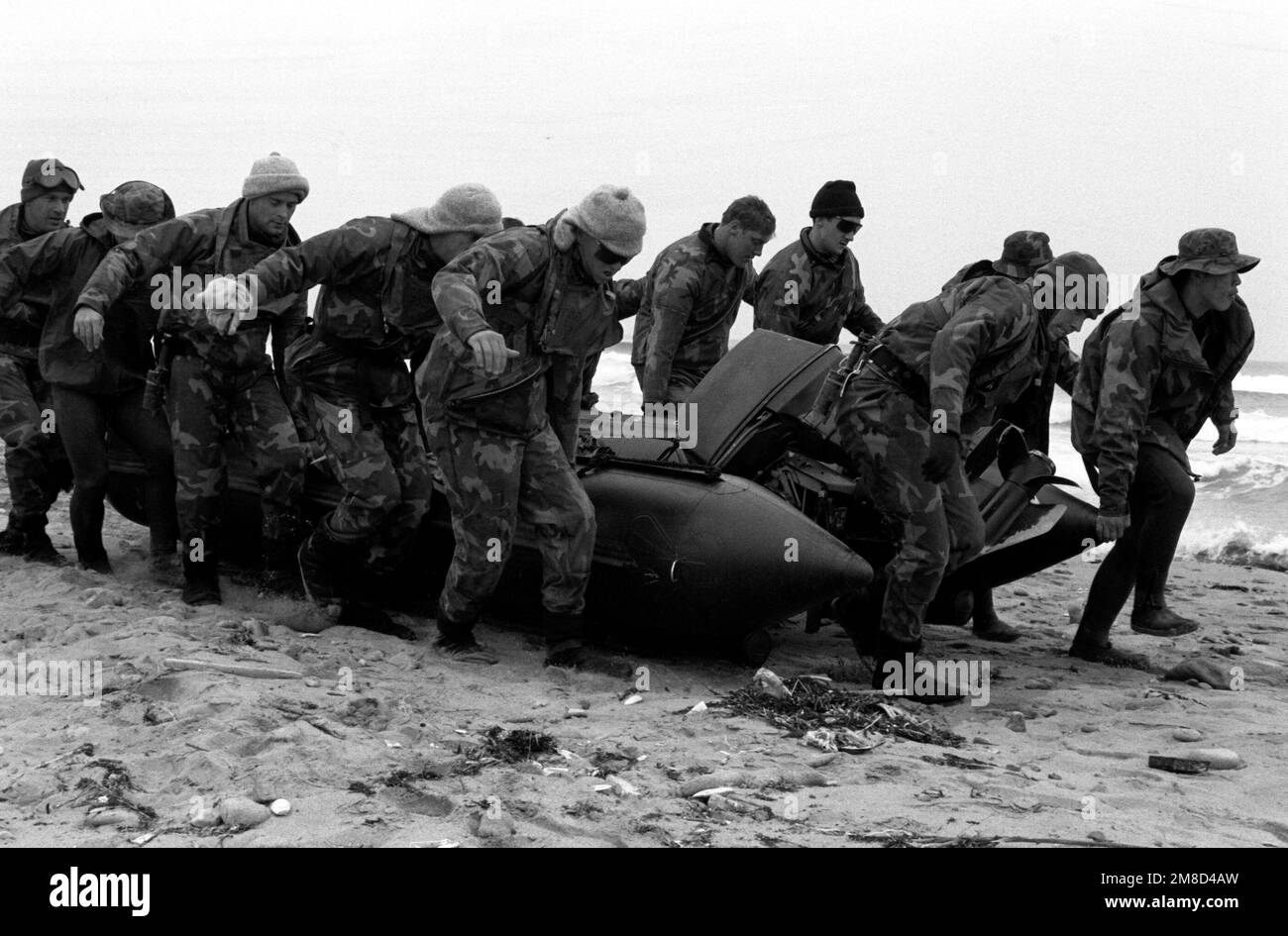 Members of a Marine reconnaissance platoon carry an inflatable boat along the beach on D-day of ...