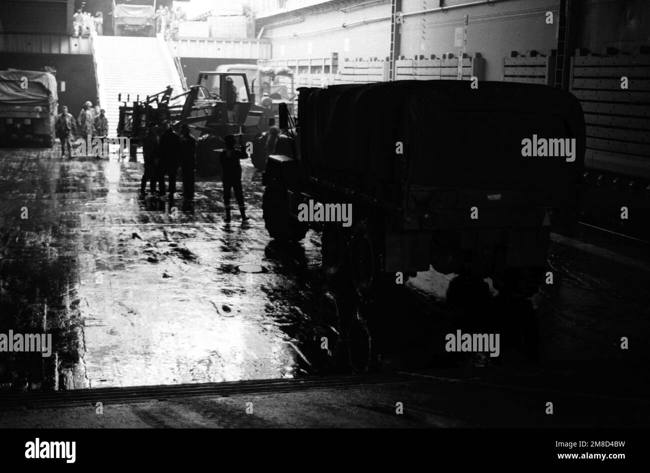 An M-923 5-ton cargo truck is moved into position in the well deck of ...