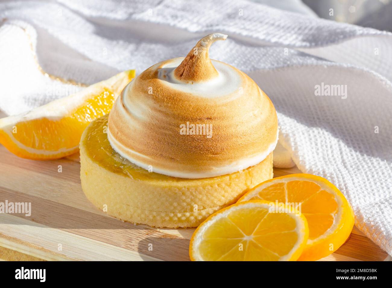 Yellow lemon tart with meringue and fresh lemons on the kitchen table ...