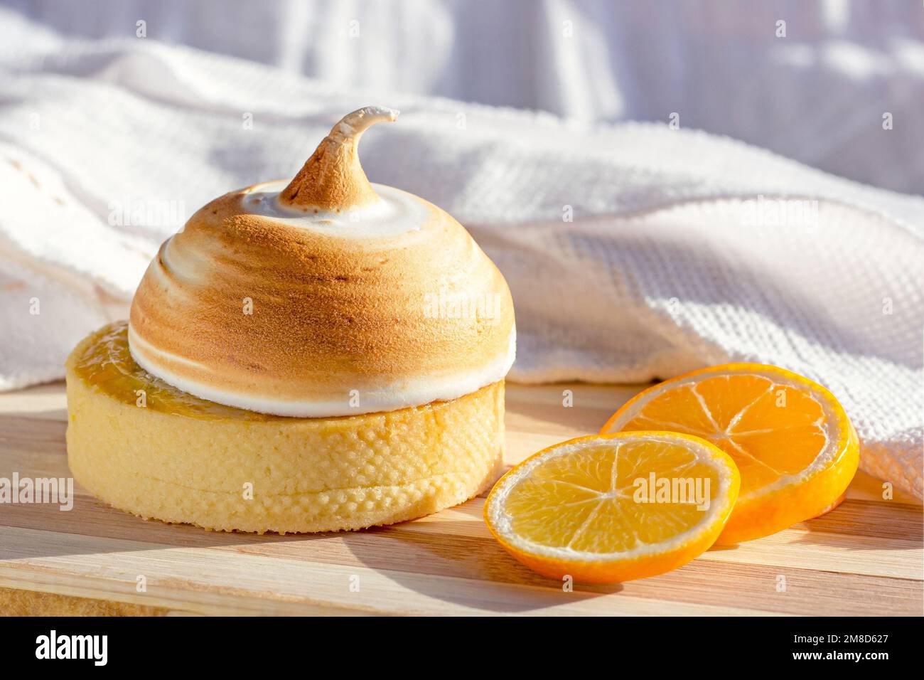 Yellow lemon tart with meringue and fresh lemons on the kitchen table ...