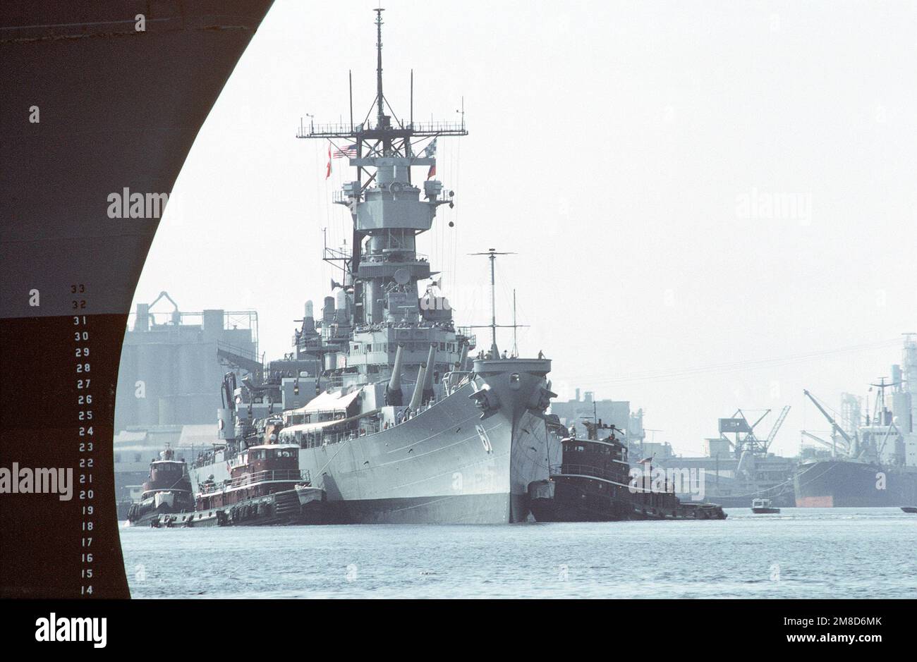 Tugs assist the battleship USS IOWA (BB 61) along the Elizabeth River on its transit to Naval ...