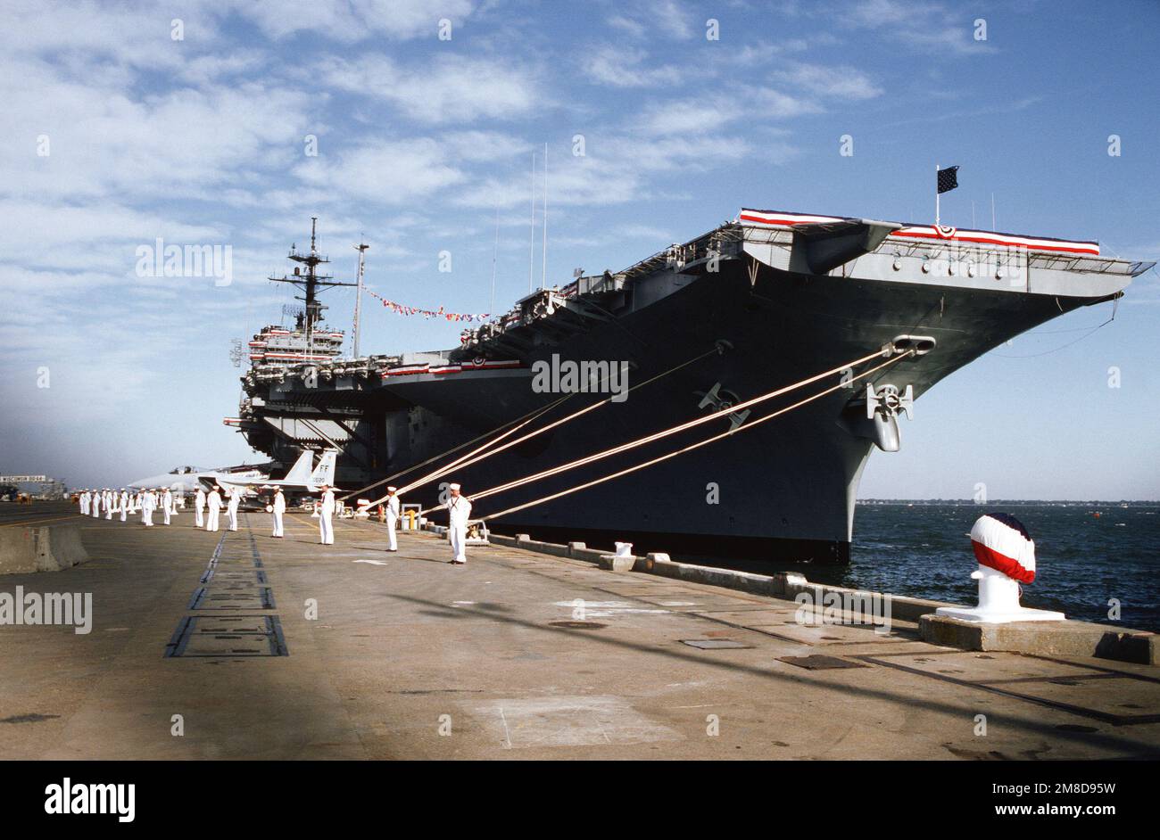 Sailors stand by on the pier beside the aircraft carrier USS JOHN F ...
