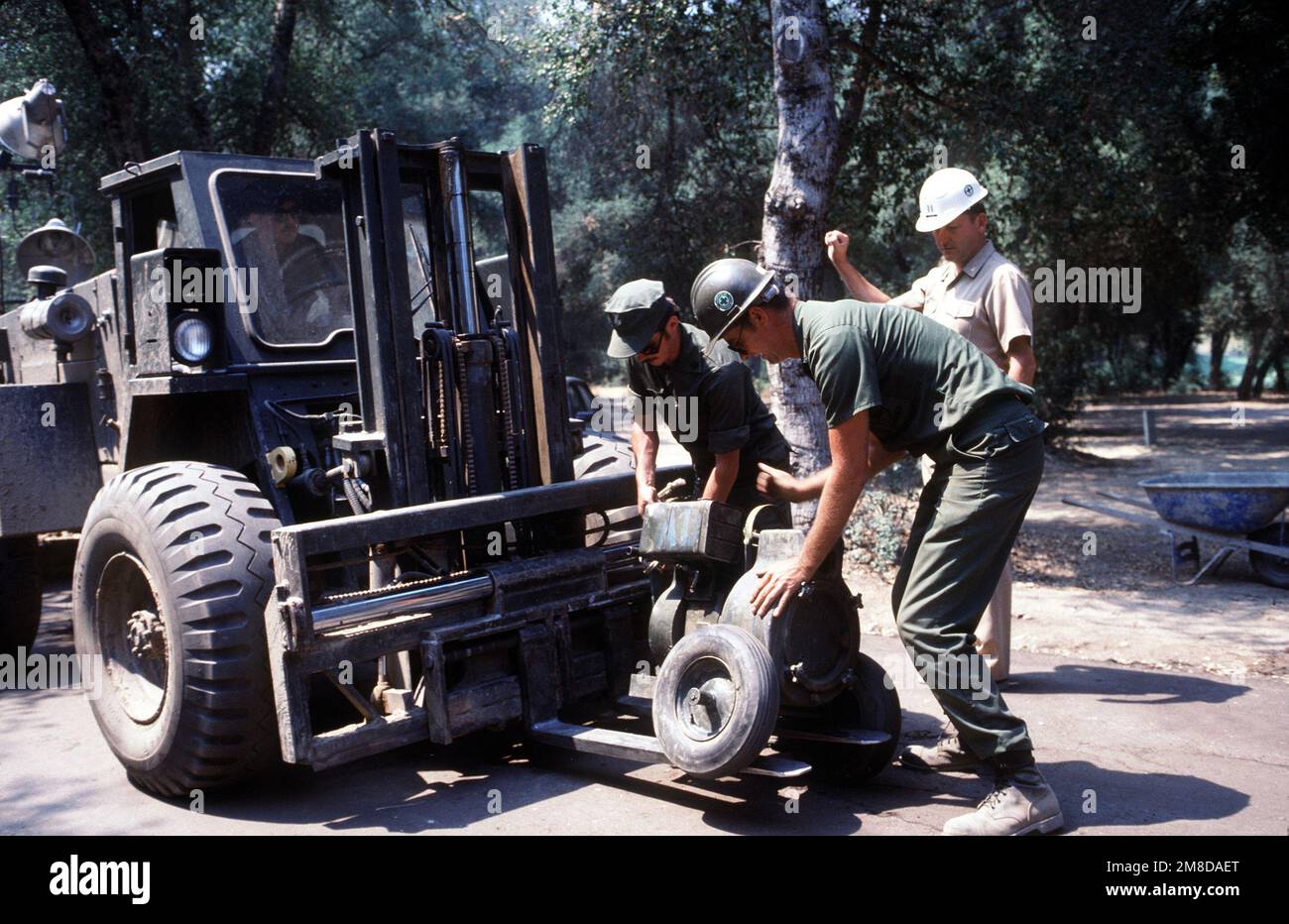 Two members of a Navy mobile construction battalion push a water pump ...