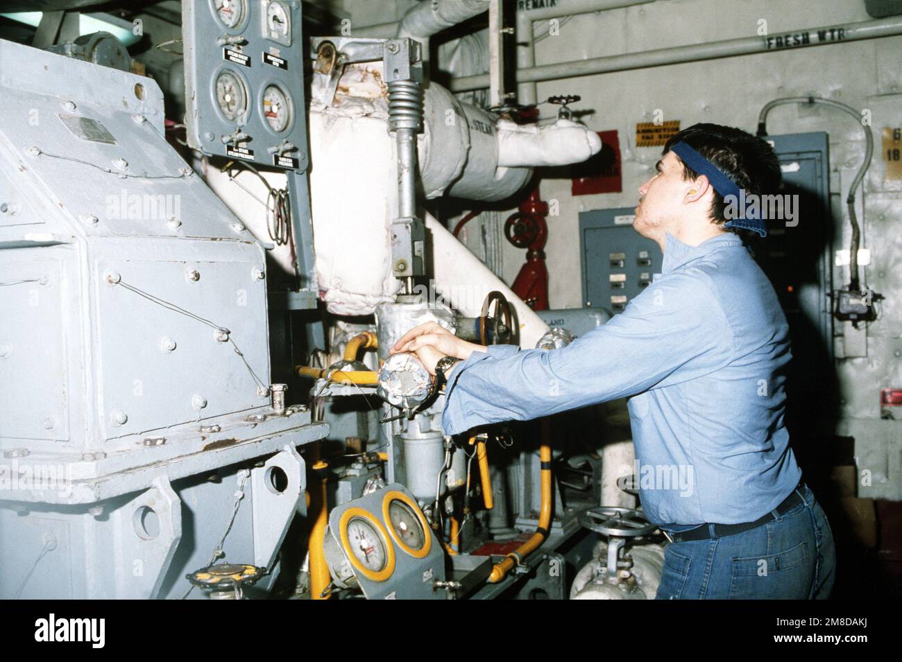 A sailor monitors the pressure gauges on one of the boilers aboard the ...