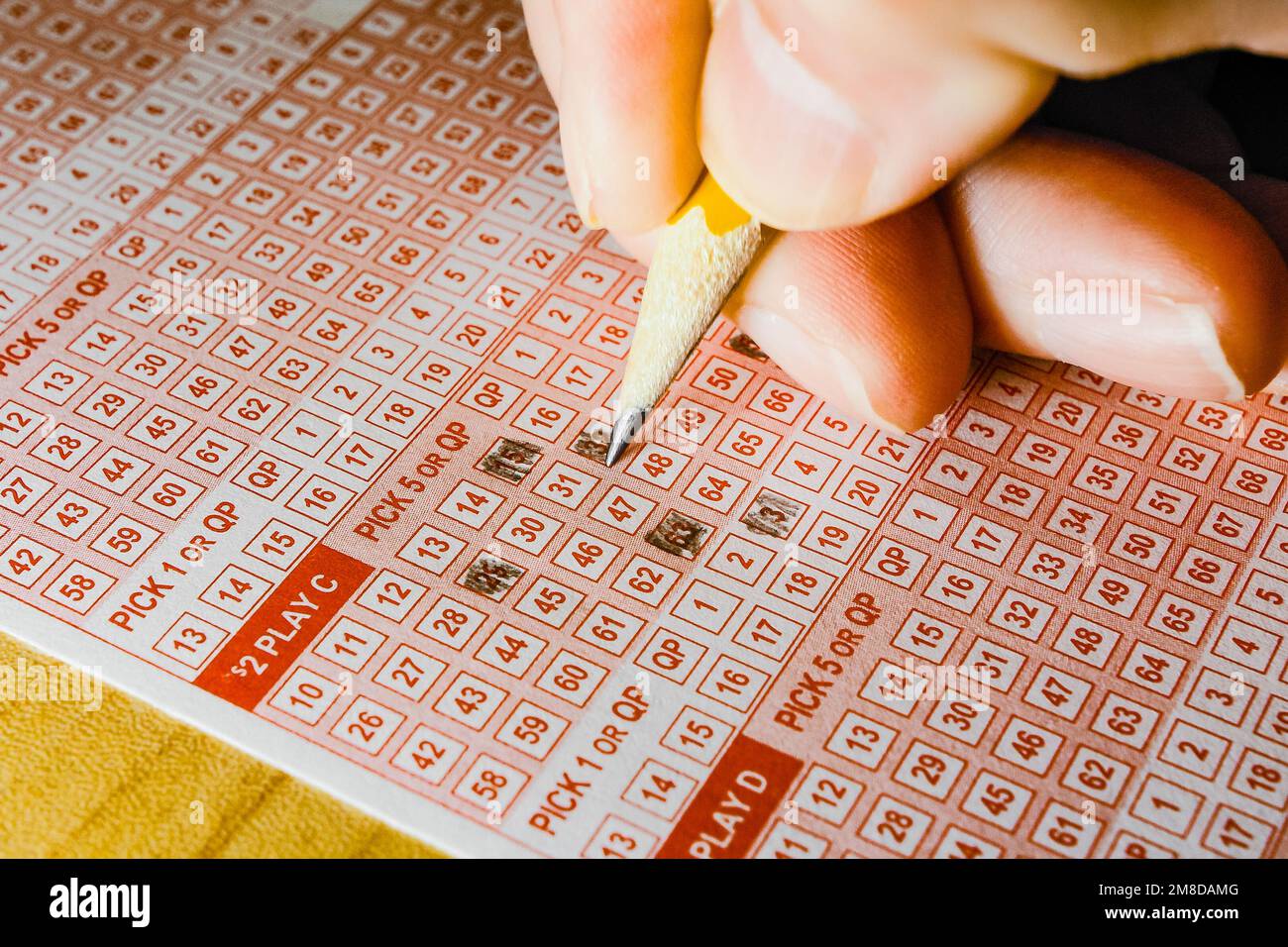 Close-up of person's hand choosing and marking lottery numbers with a ...