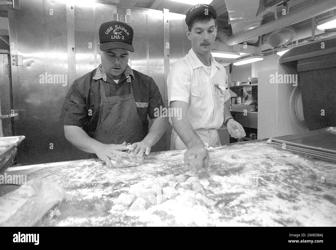 Two mess management specialists aboard the amphibious assault ship USS ...