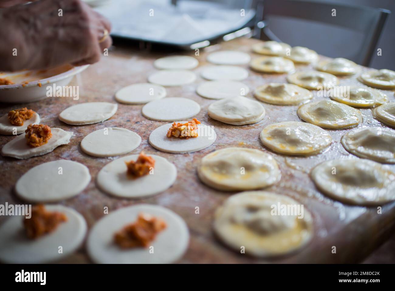 Filling and sealing puff pastry dumplings in a kitchen. Lifestyle Stock ...