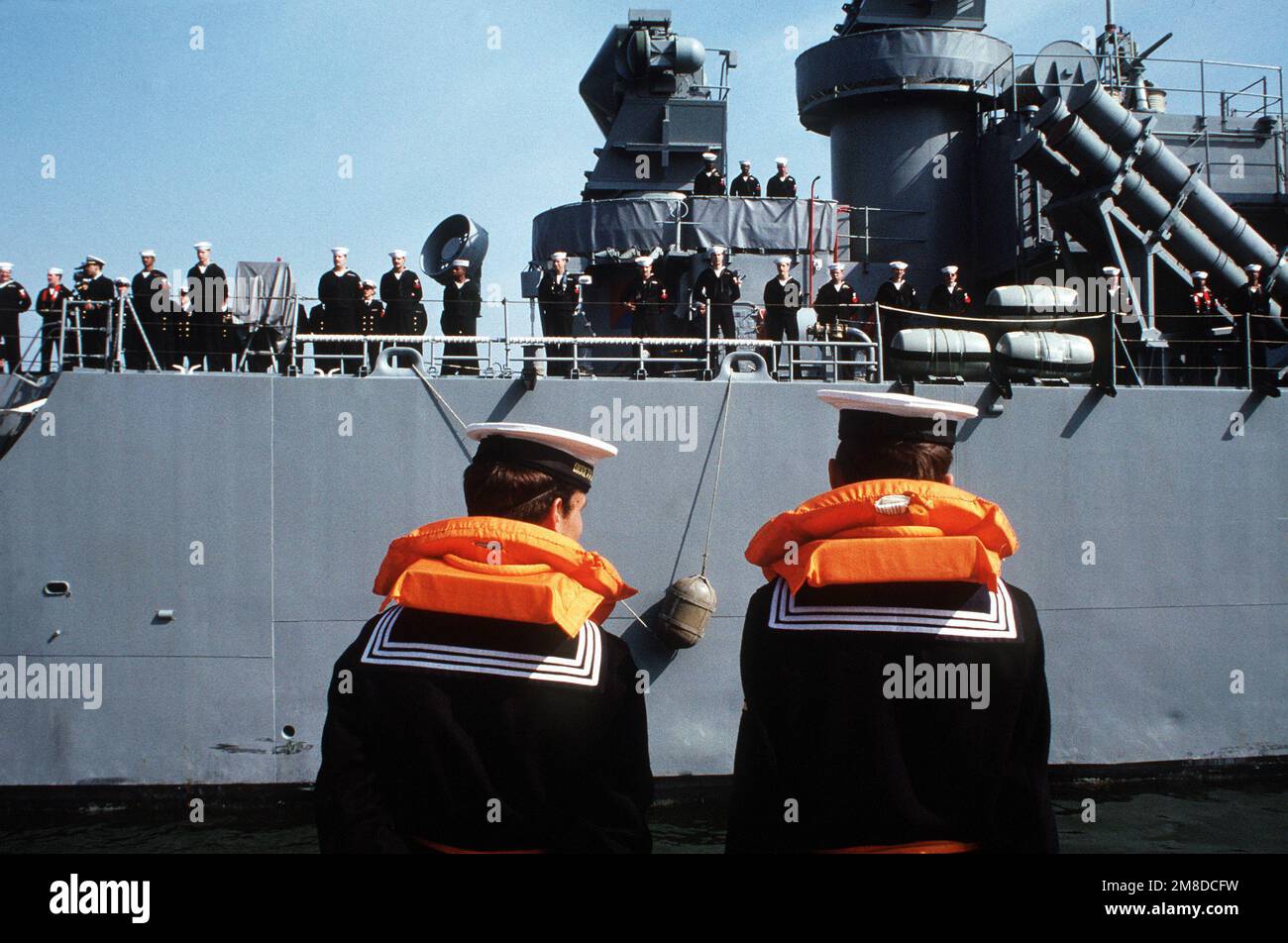 Two Polish sailors watch from the pier as crew members aboard the ...