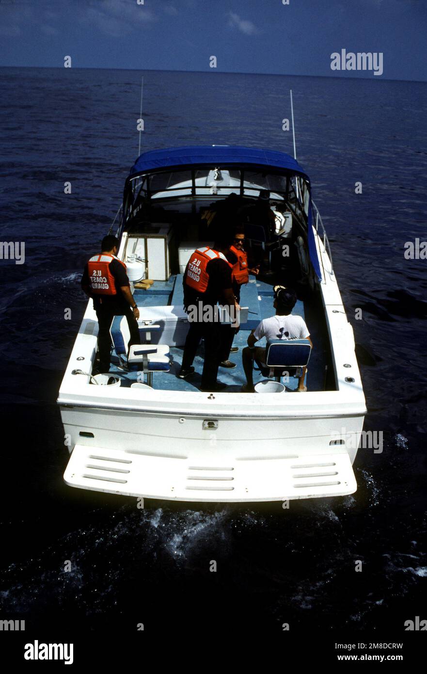 Members of a Coast Guard law enforcement team talk with a fishing boat ...