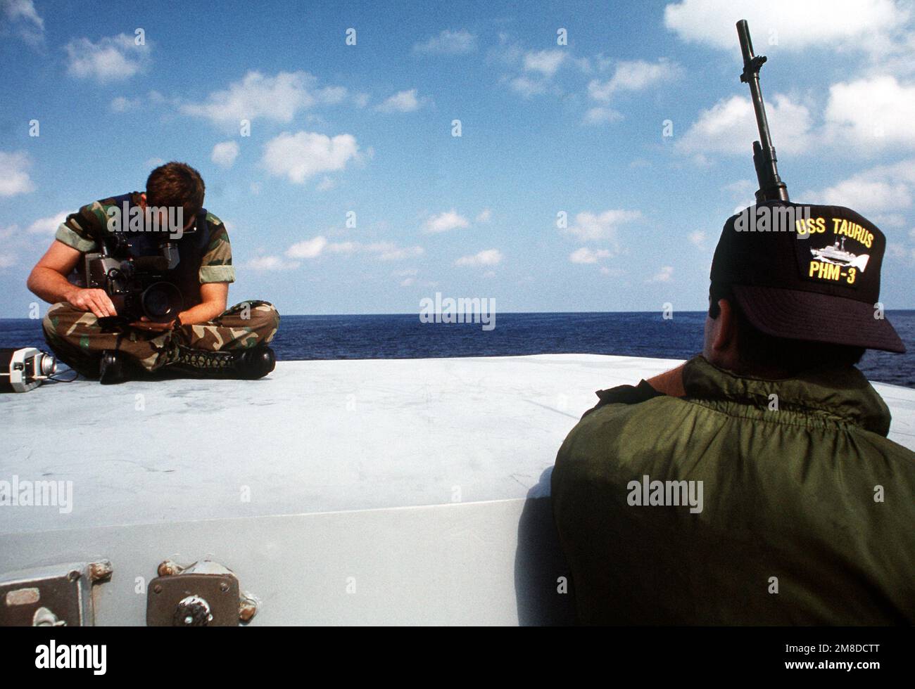 A Navy photographer photographs a sailor standing guard aboard the ...