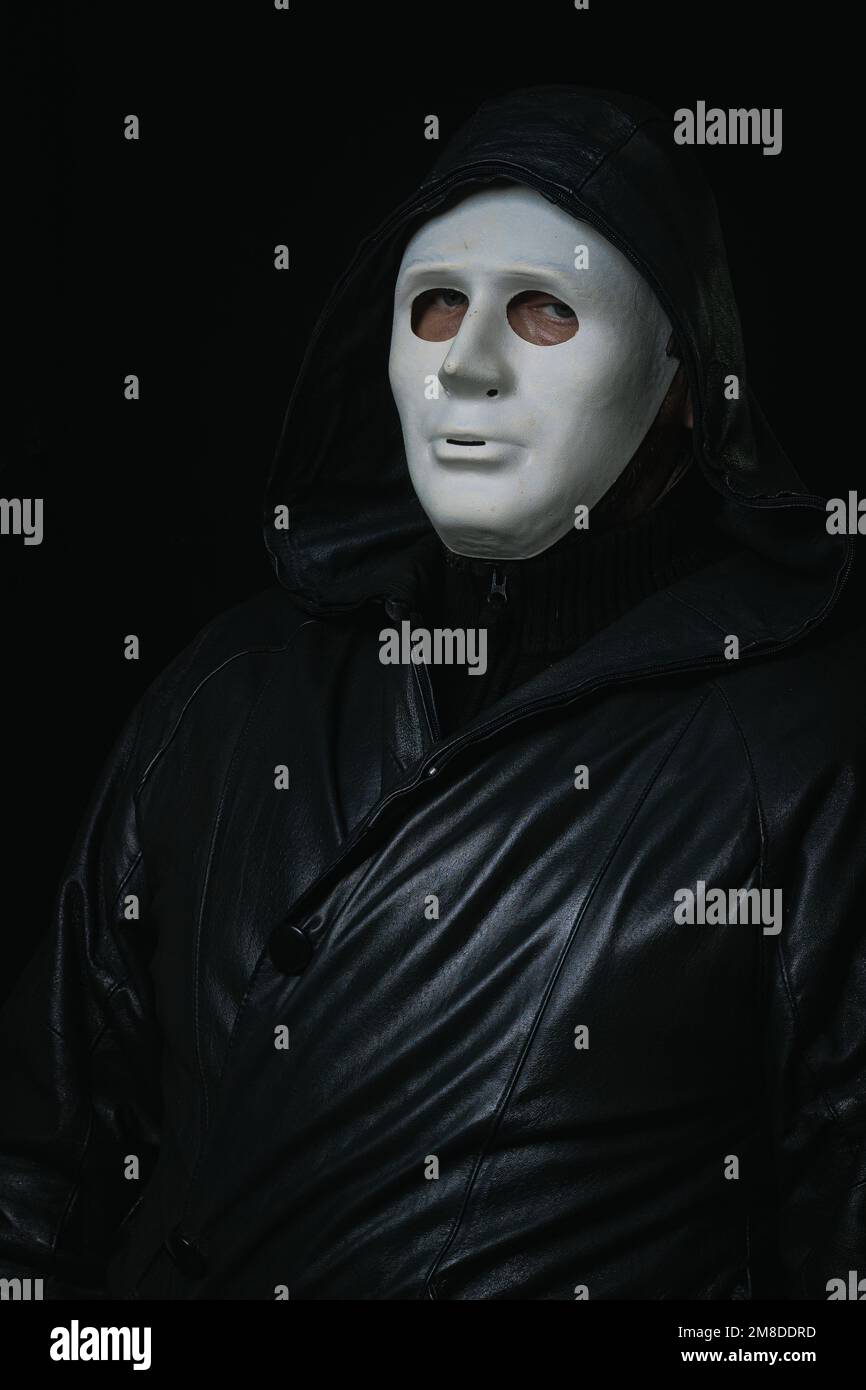 Man in terrible face mask staring at camera against dark background ...