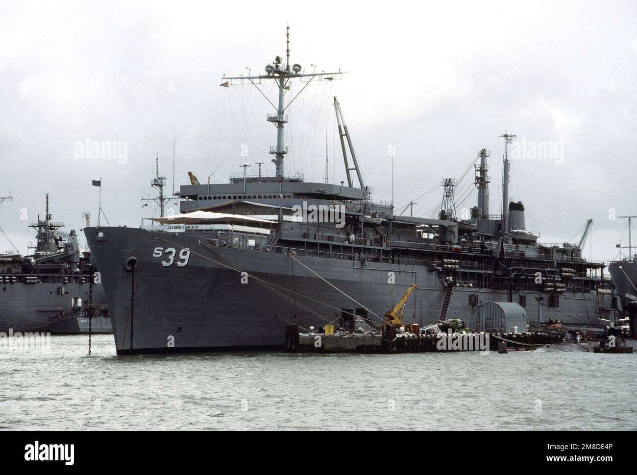 A port bow view of the submarine tender USS EMORY S. LAND (AS 39) tied ...