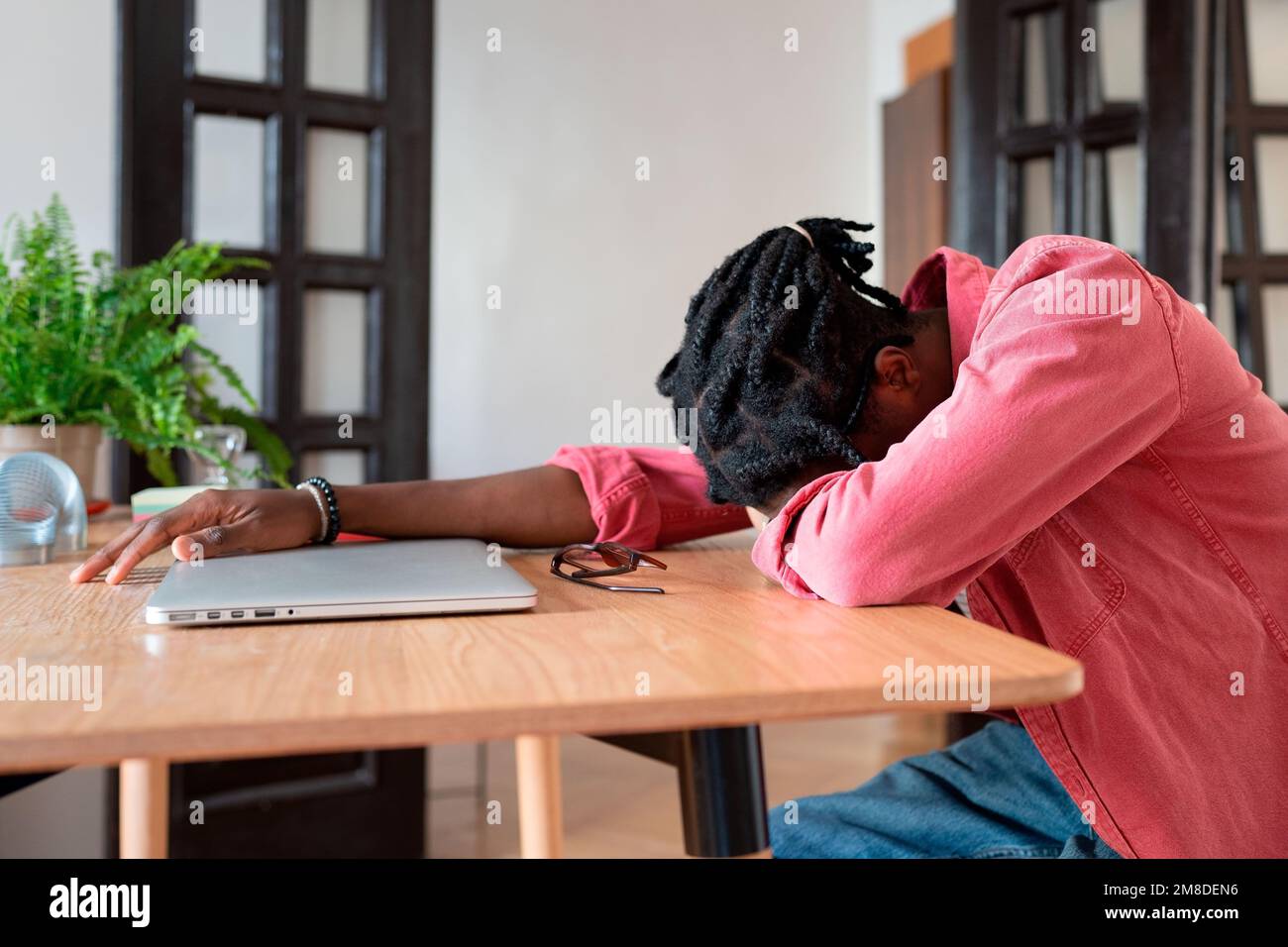 Exhausted overloaded African guy remote worker sleeping on desk ...