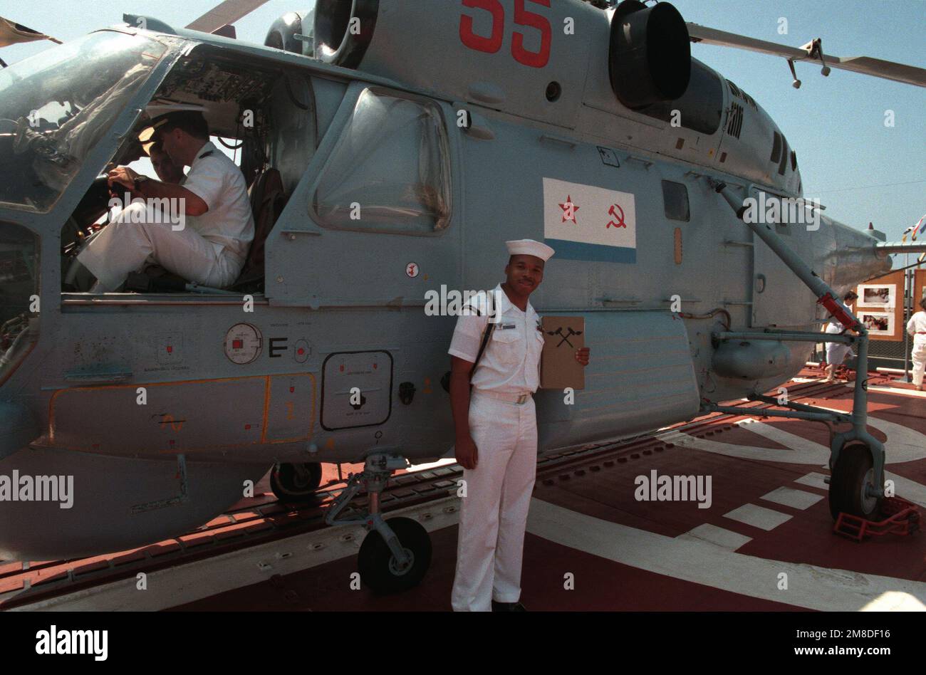 An American sailor stands in front of a Soviet Ka-27 Helix helicopter ...