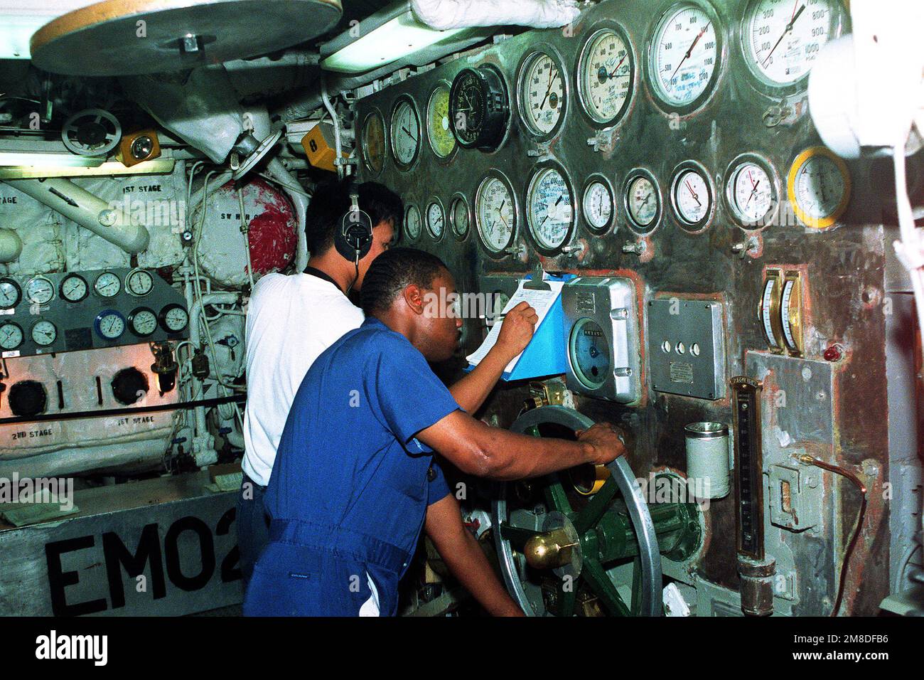 Crew members monitor guages in the No. 1 engine room aboard the guided ...