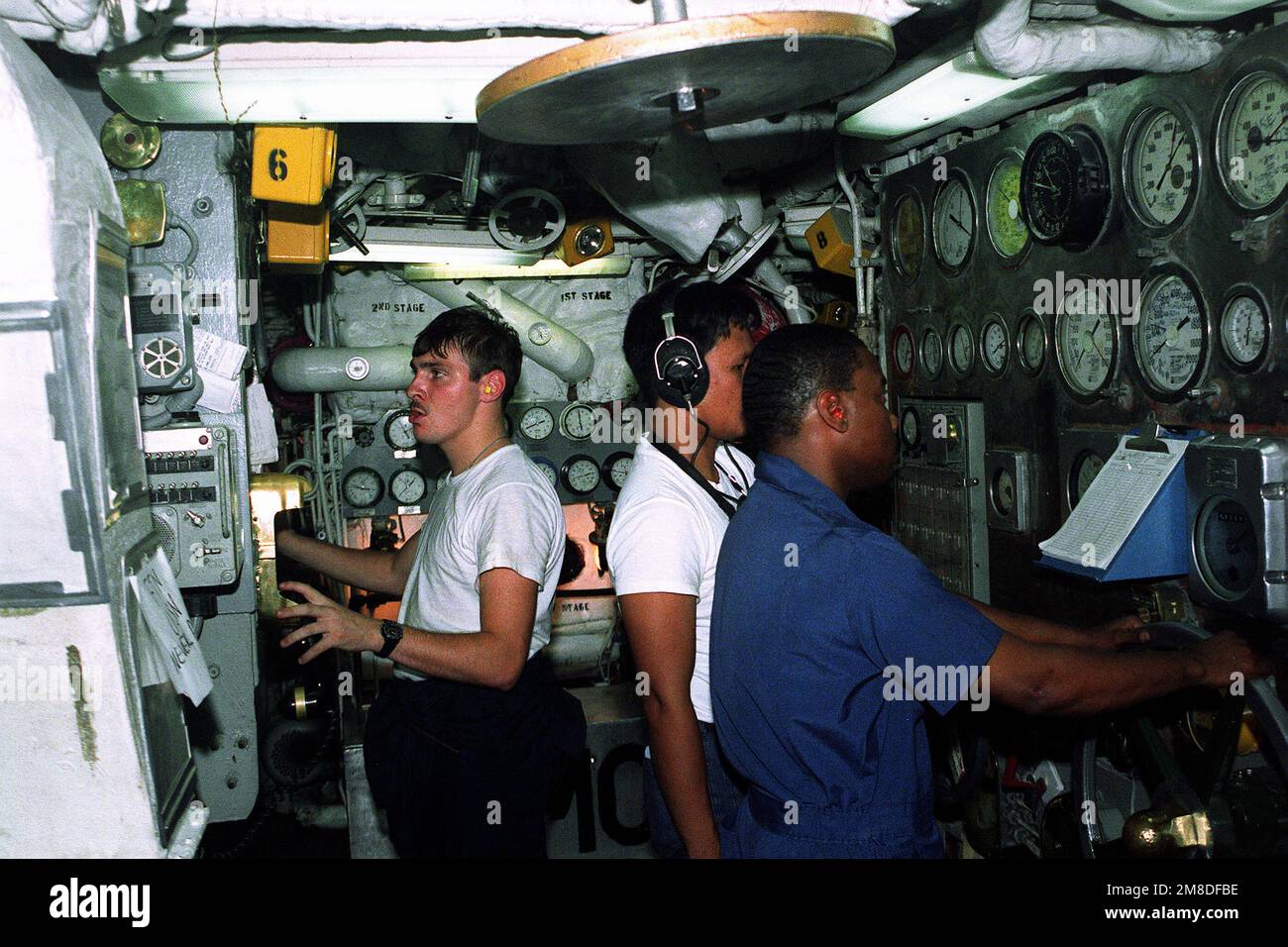 Crew members monitor guages in the No. 1 engine room aboard the guided ...