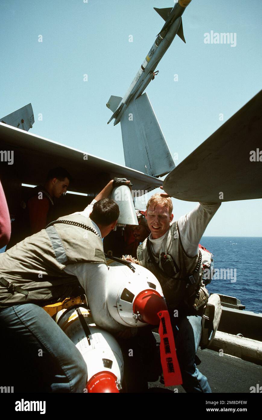 Flight deck crewmen help mount a Mark 20 Rockeye II cluster bomb ...