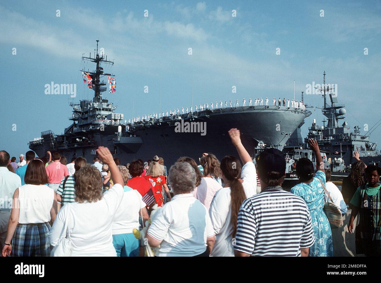 Crew members man the rails aboard the amphibious assault ship USS GUAM ...