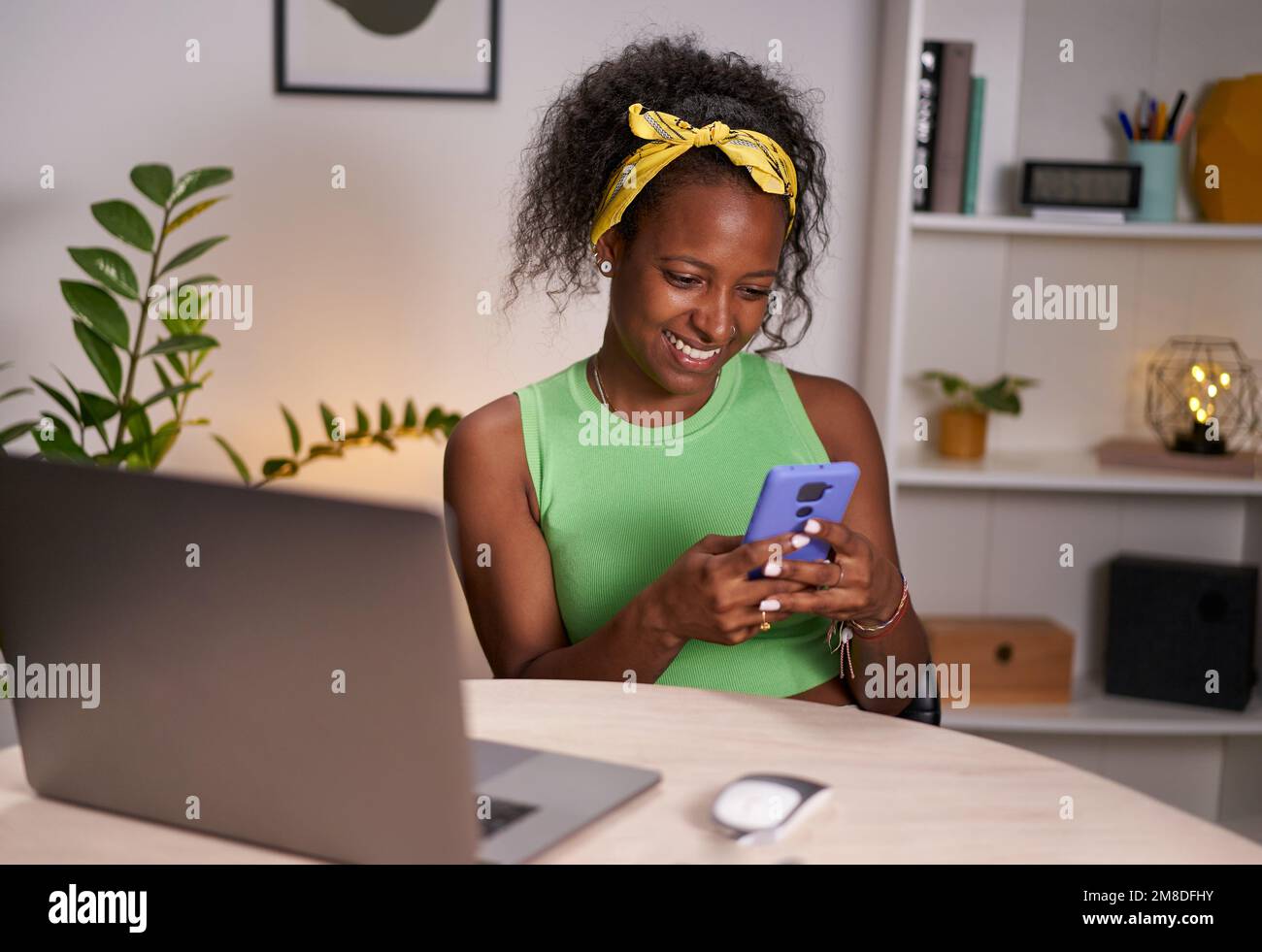 Young African woman using phone at home office. Happy girl typing on ...