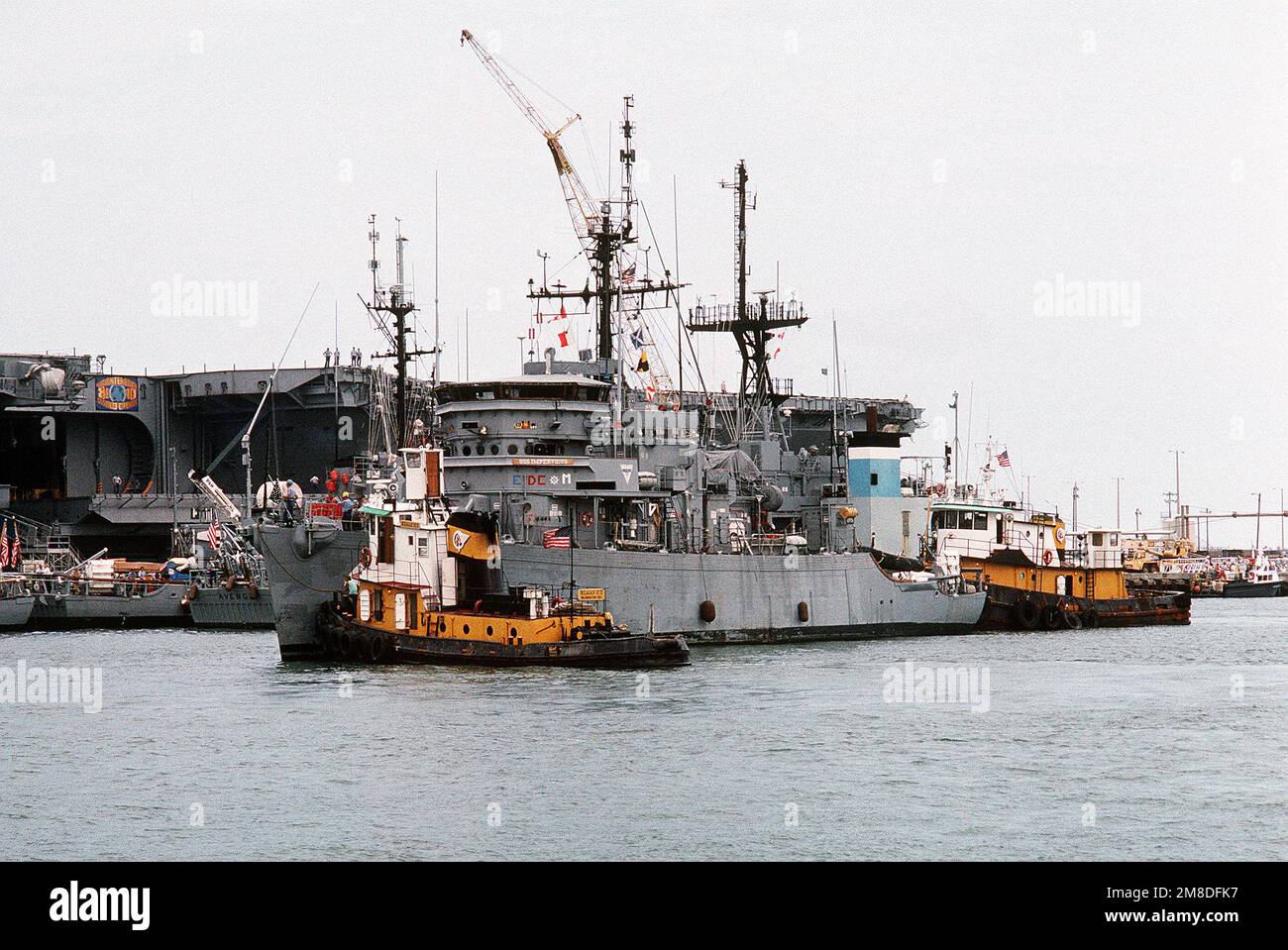 Commercial harbor tugs maneuver the ocean minesweeper USS IMPERVIOUS ...