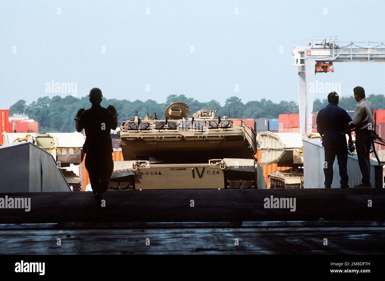 A member of the 24th Infantry Division guides the driver of an M-1 ...
