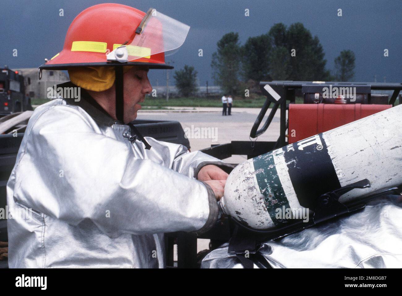 A firefighter checks the air tank on the back of another firefighter ...