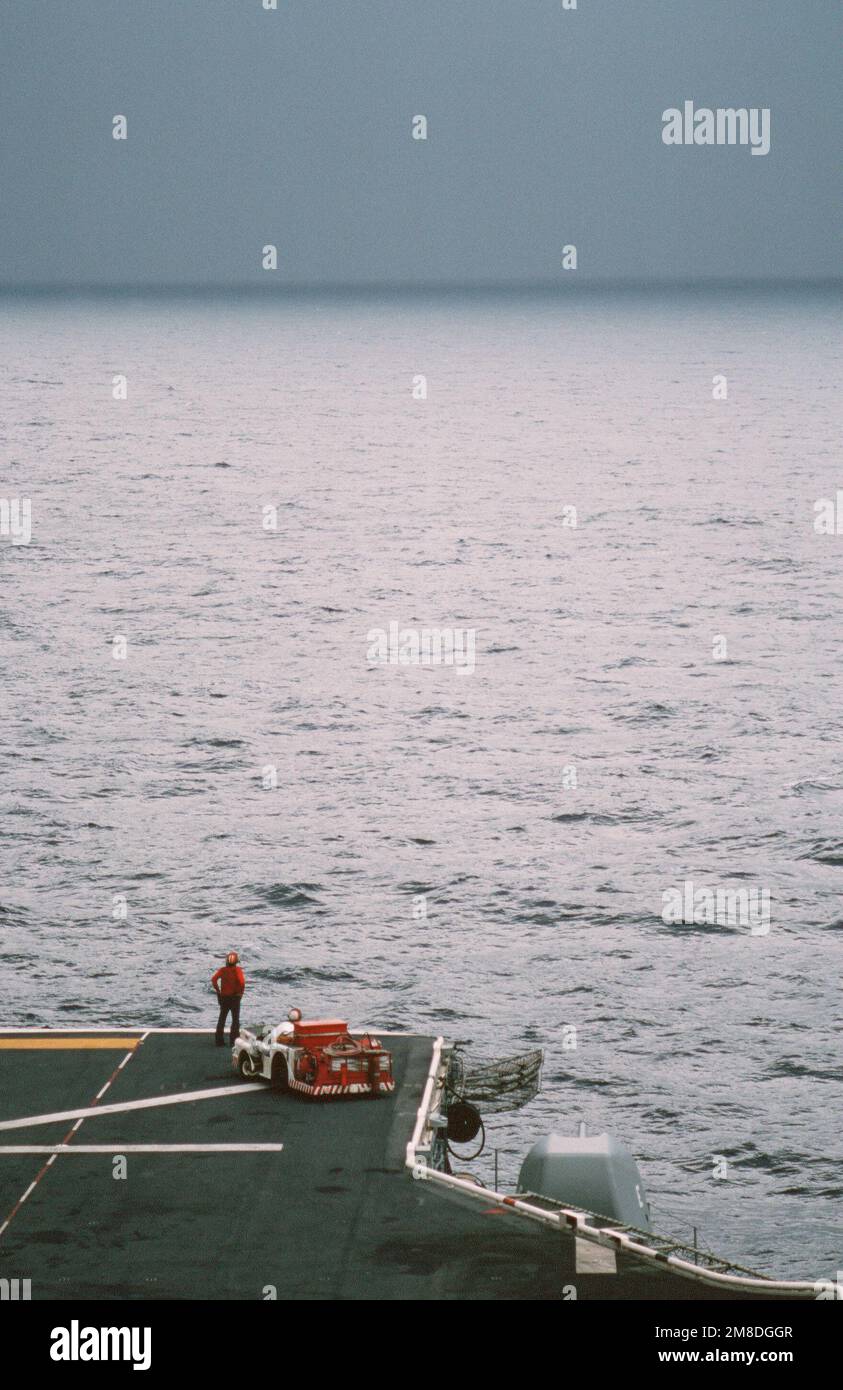 Two flight deck crewmen wait for flight operations to resume aboard the ...