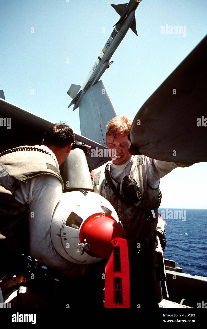 Flight deck crewmen help hold up a Mark 20 Rockeye II cluster bomb as ...