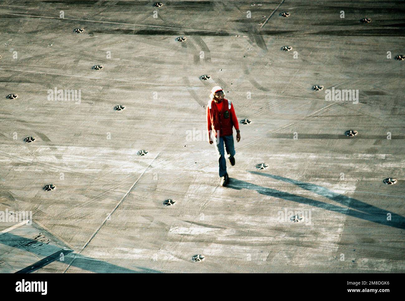 An aviation ordnanceman walks across the flight deck of the nuclear ...